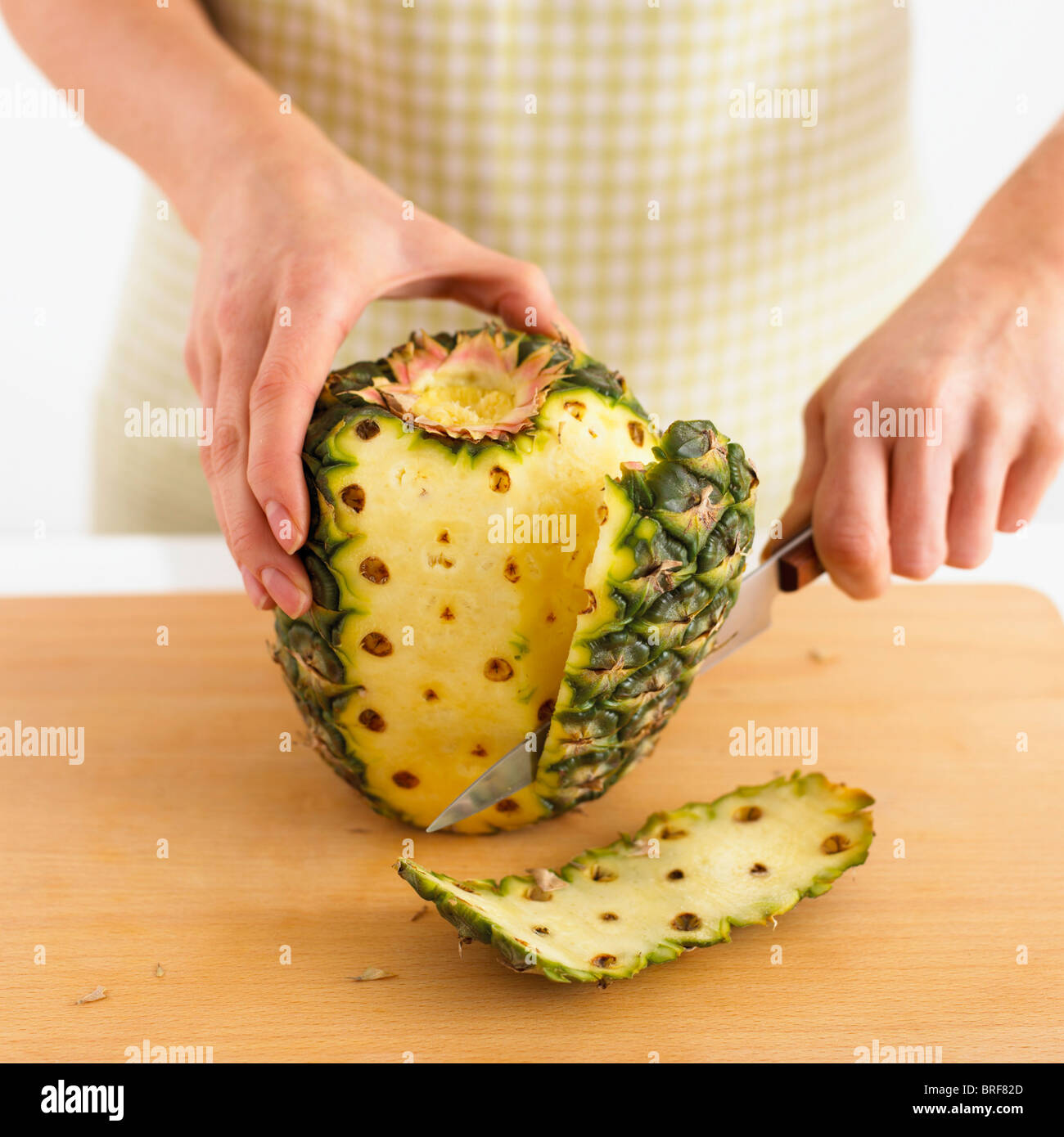 Woman slicing skin off pineapple Stock Photo - Alamy