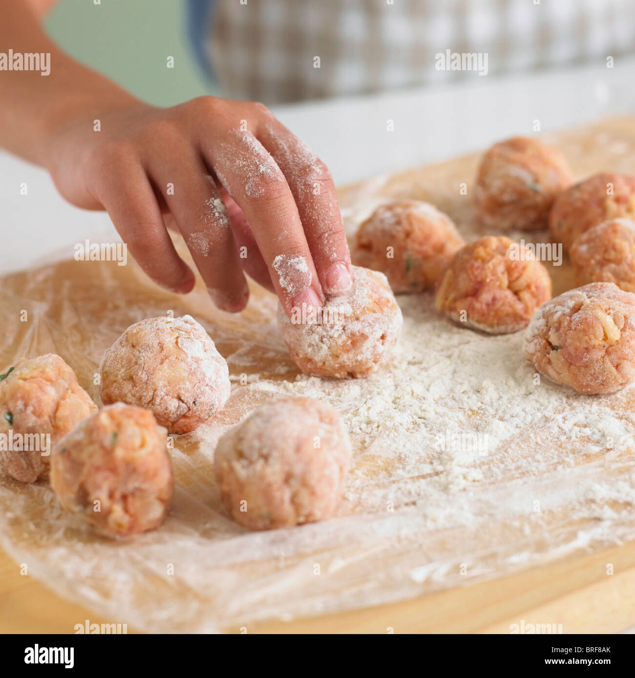Woman rolling minced meatballs into flour Stock Photo - Alamy