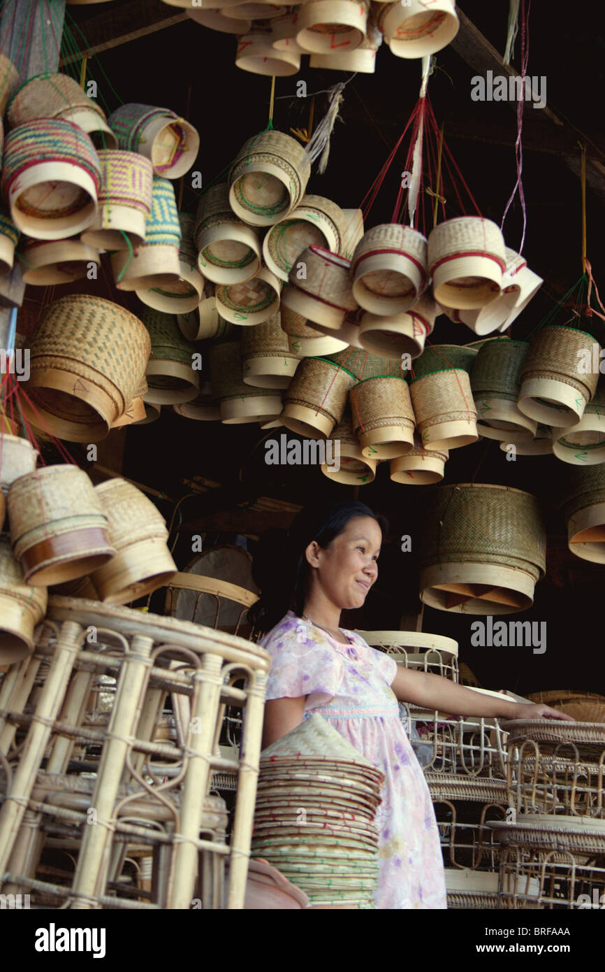 A woman who works as a rice basket vendor tends to her shop at a market ...