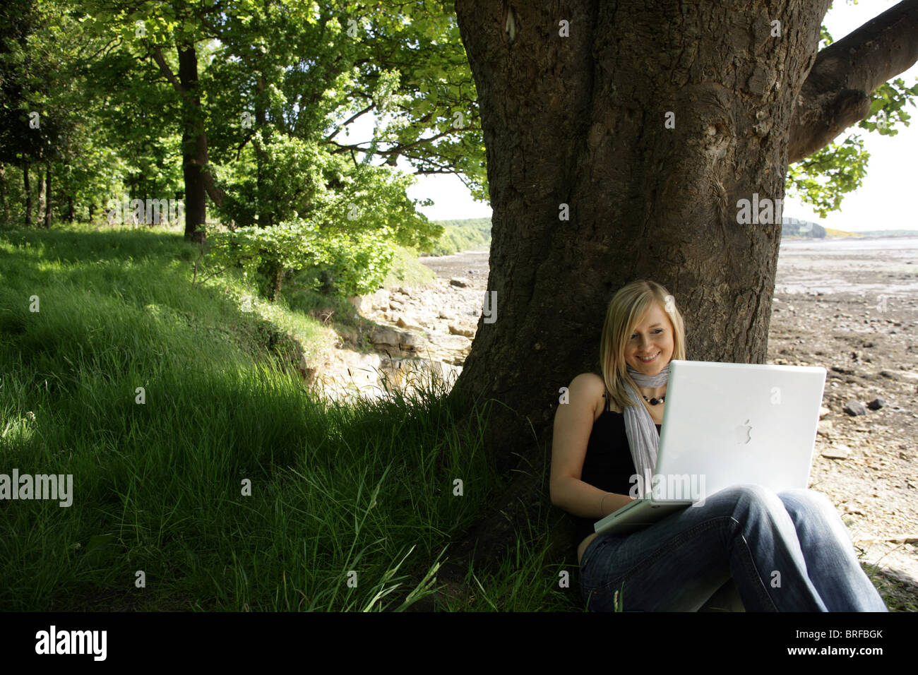 Young woman sitting outside using her apple laptop Stock Photo - Alamy