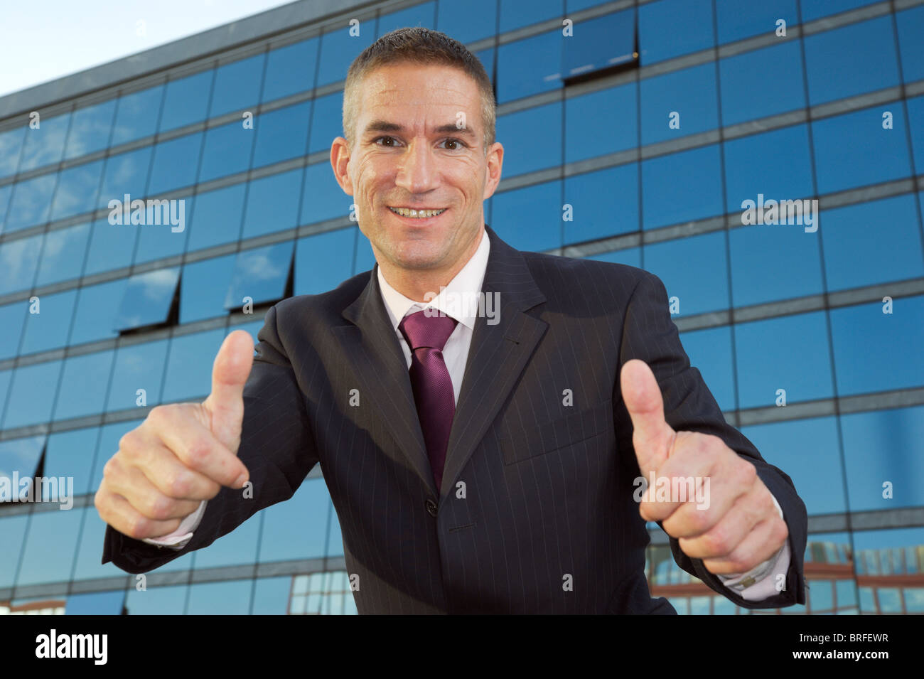tough looking man in a suit, smiling and doing all right sign, business ...