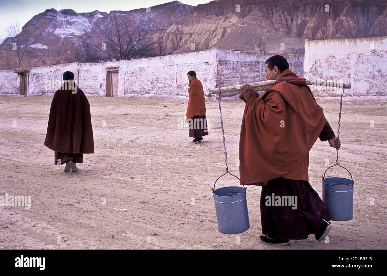 Tibetan buddhist monks collect drinking water from a well inside the ...
