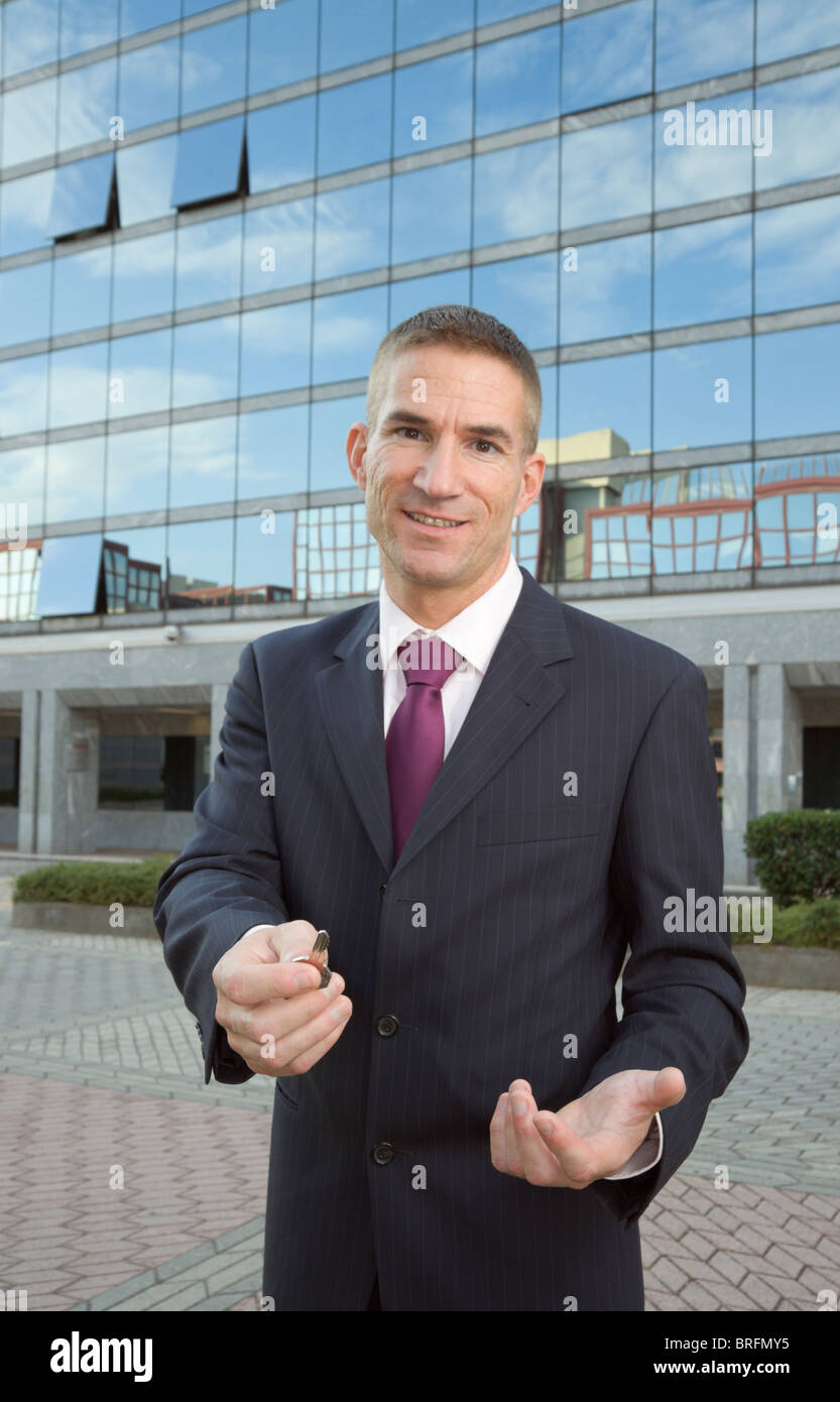 tough looking man in a suit, holding a house/office key, business ...