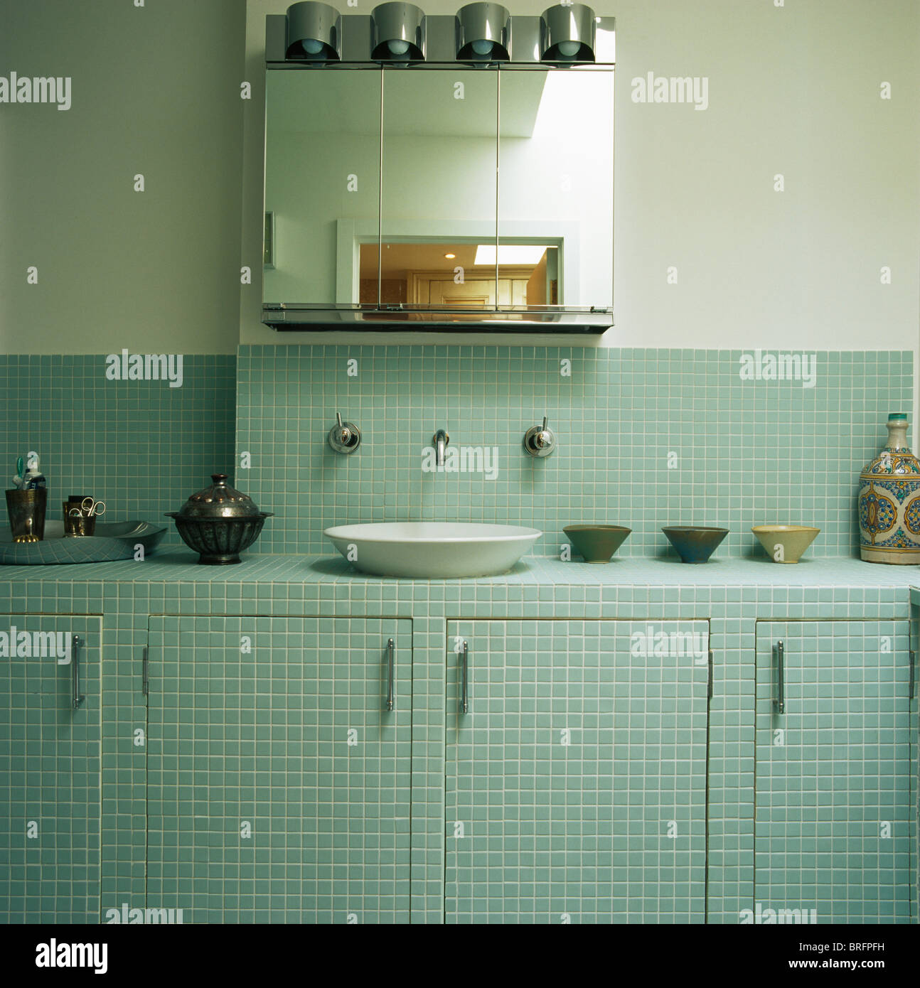 Glass-fronted cabinet above basin in pastel green mosaic-tiled vanity ...