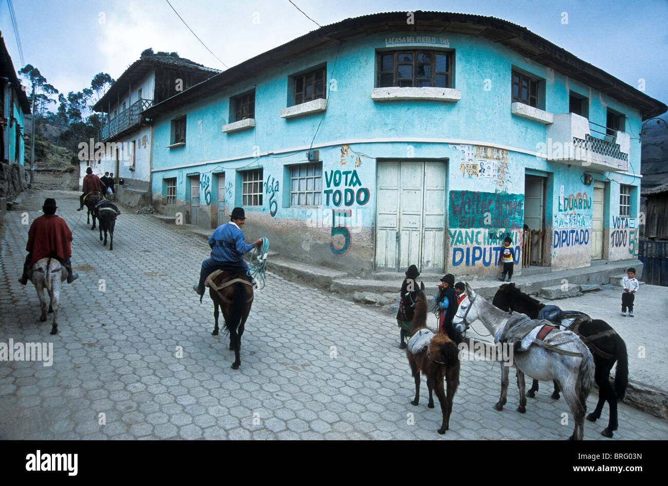 Native indian farmers riding on donkeys through the town of Angamarca ...