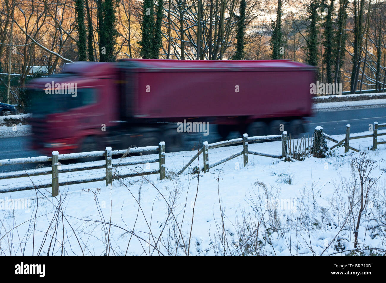 Large lorry driving along country road in wintry weather after heavy ...