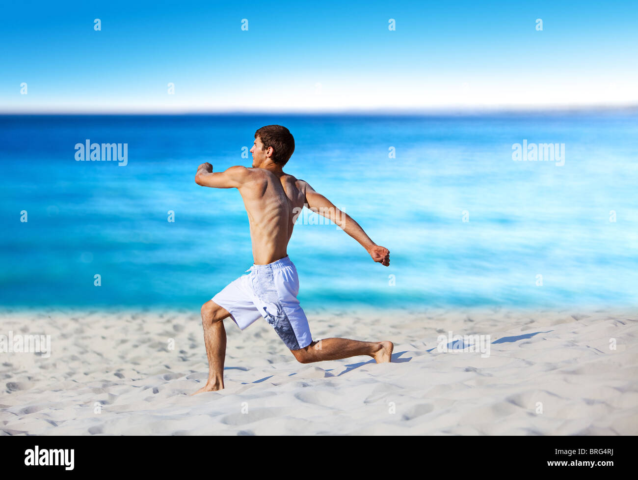 Young man running on beach Stock Photo - Alamy