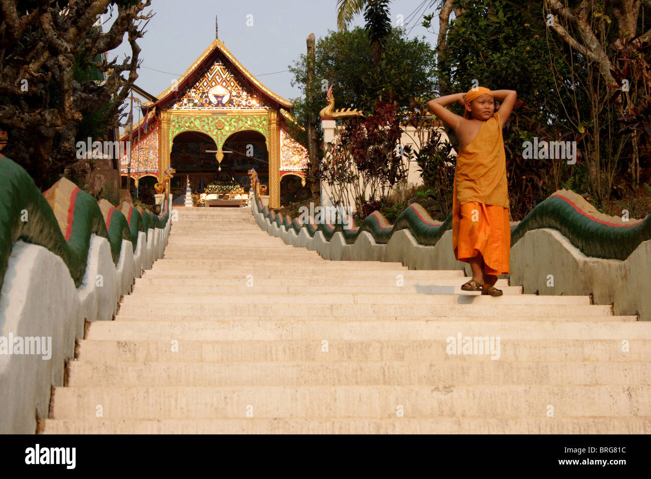 A novice Buddhist monk walks down a long flight of stairs at a temple ...