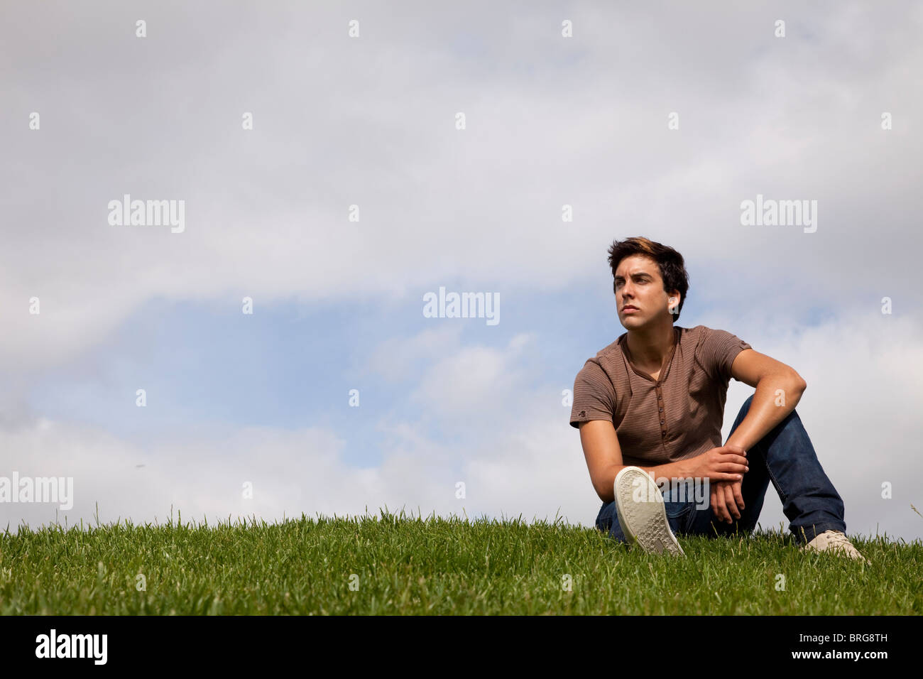 Young men sited on the grass looking away Stock Photo - Alamy