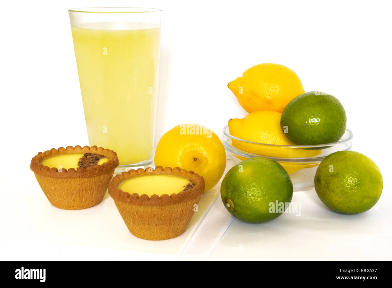healthy snacks. Lemon tarts, lemons, limes and a glass of lemonade set ...