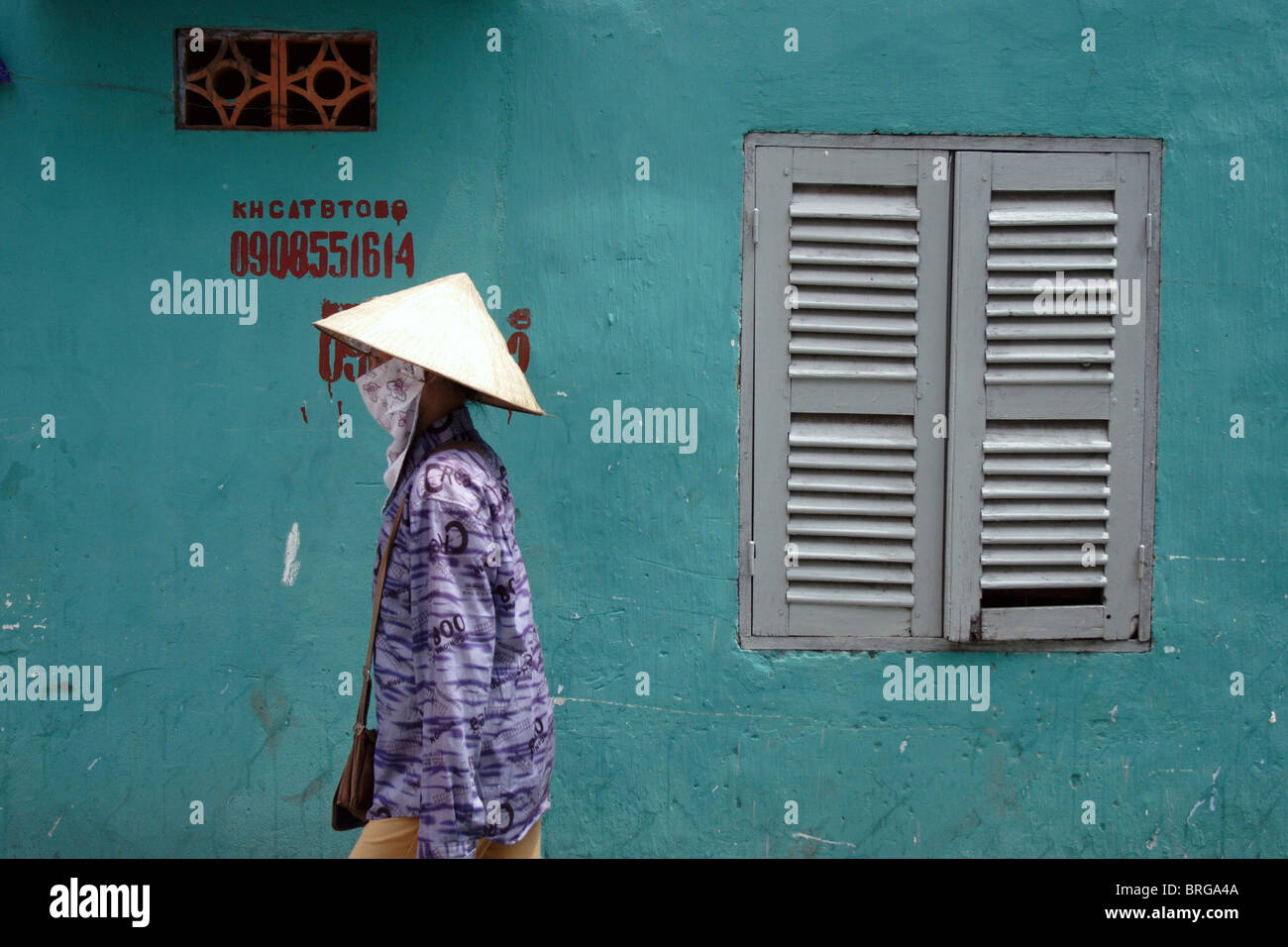 A masked woman walks by one of thousands of stenciled signs seen in ...