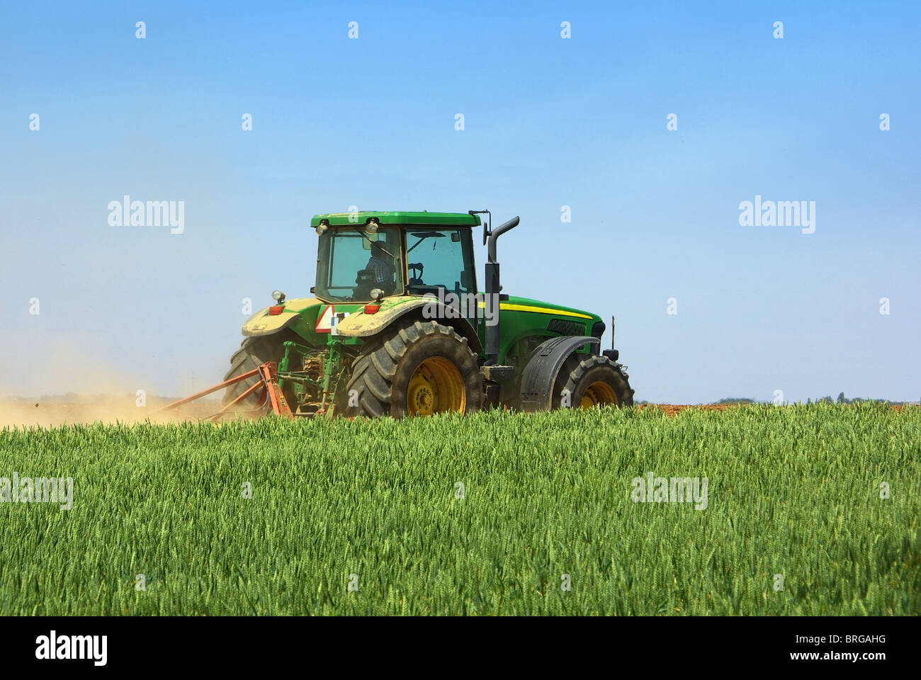 Green tractor in green field Stock Photo - Alamy