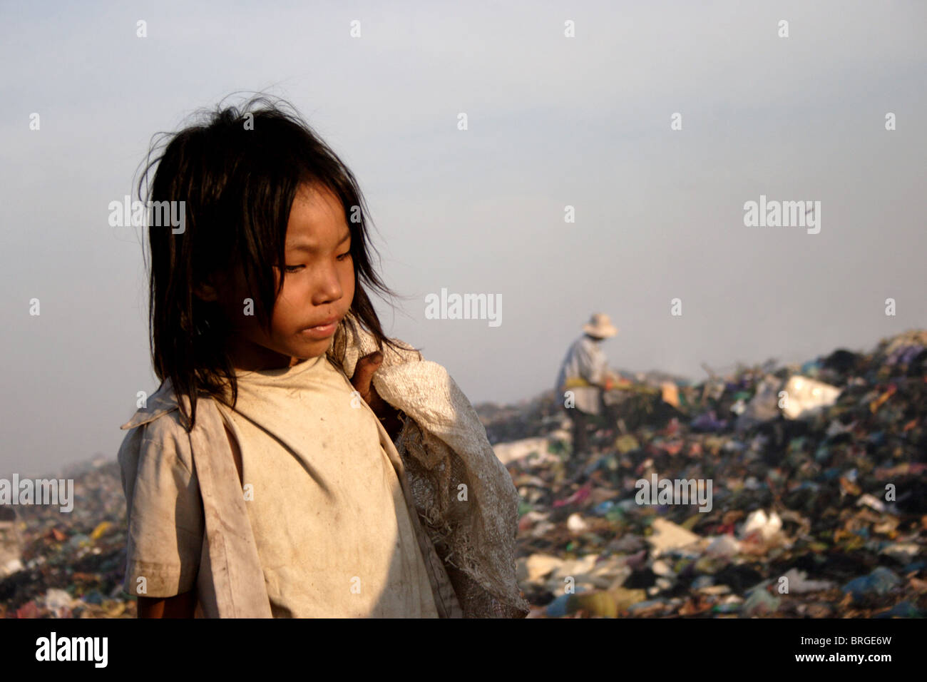 A young girl who works as child laborer carries a bag of garbage at the ...