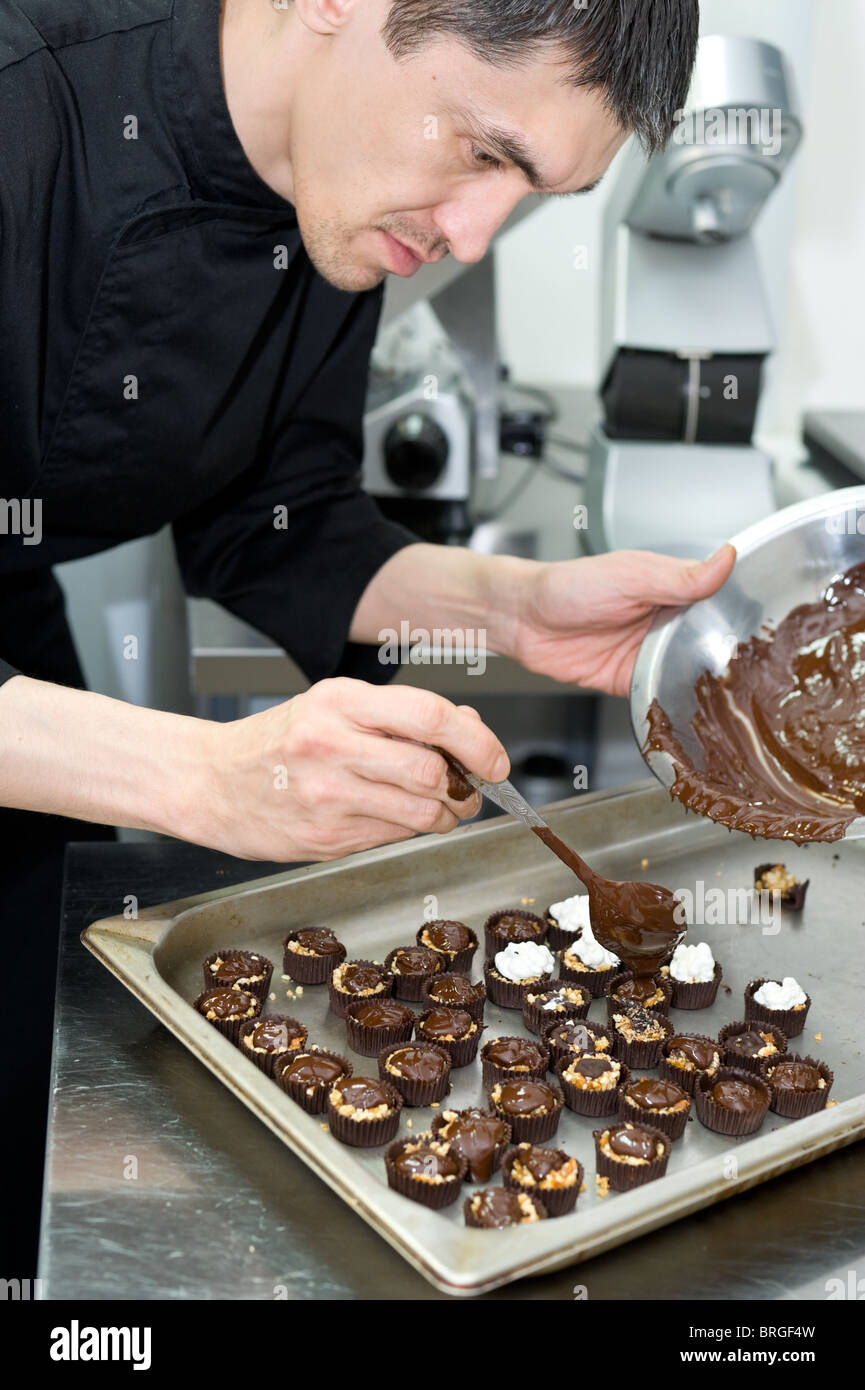 caucasian male chef makes chocolate sweets according to his own recipe ...