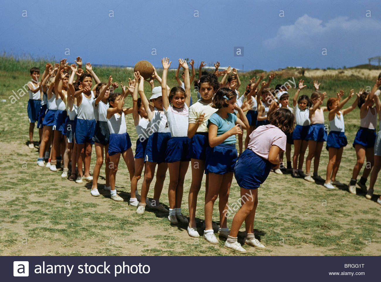 Children stand in rows to play a game of passing a ball Stock Photo ...