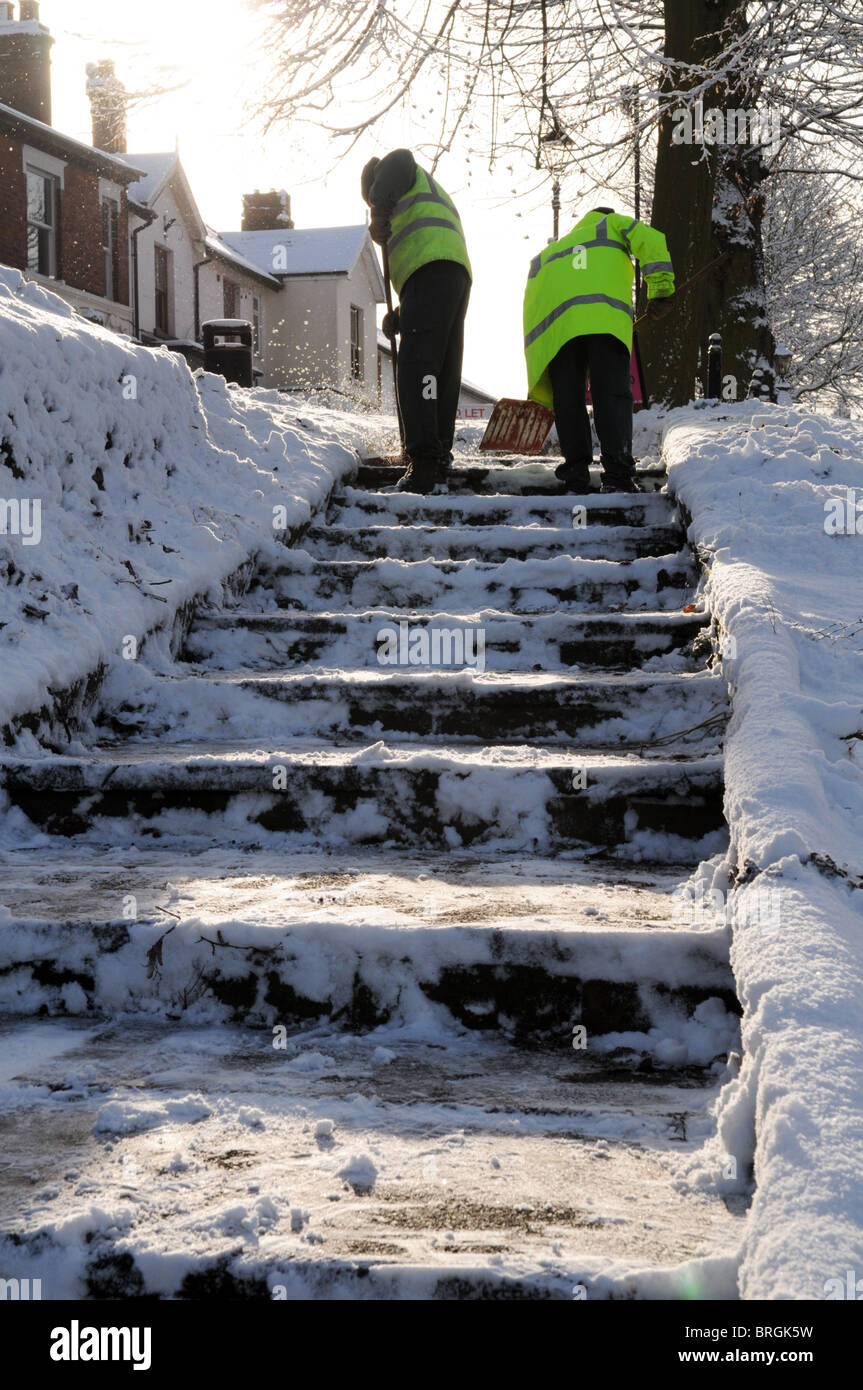 Two council workers clearing snow off steps in Tettenhall ...