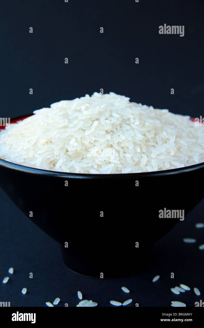 White rice in a cup of black on black background Stock Photo - Alamy