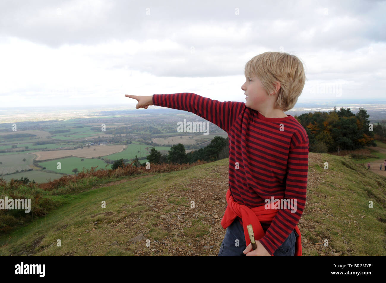 A young fair-haired boy stands on the top of the Wrekin and points over ...