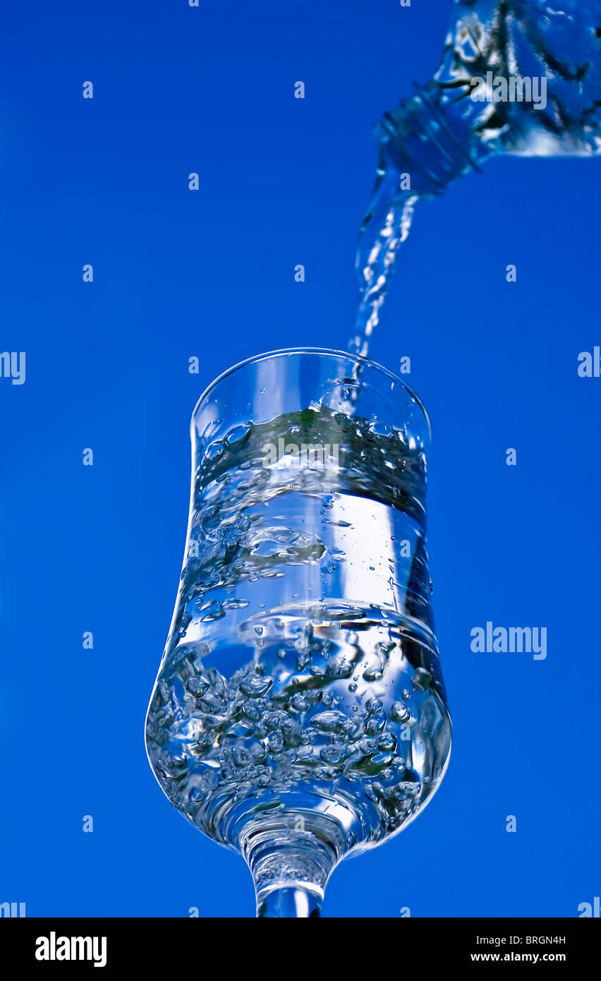 Pouring glass of water on the blue sky background Stock Photo - Alamy