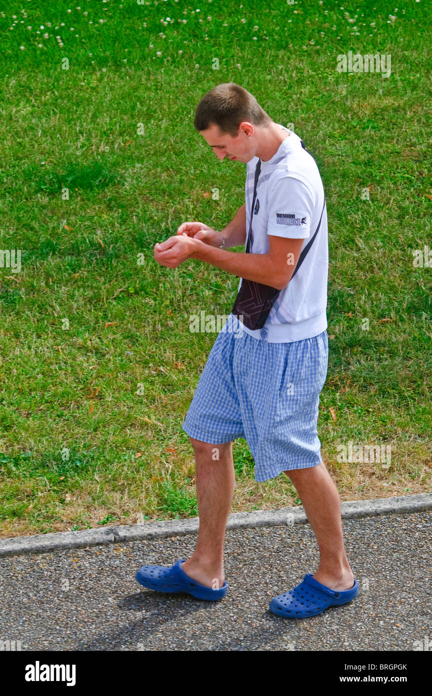 Young man walking along pavement - France Stock Photo - Alamy