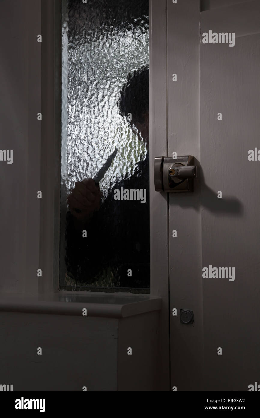 Figure of someone holding a knife outside on opaque glass window by a ...