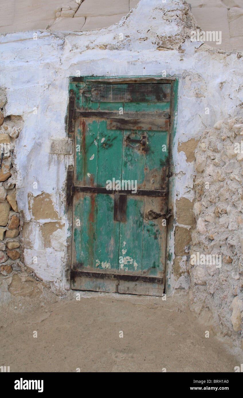 a decayed green door into the cliff face in Gozo off Malta facing the ...