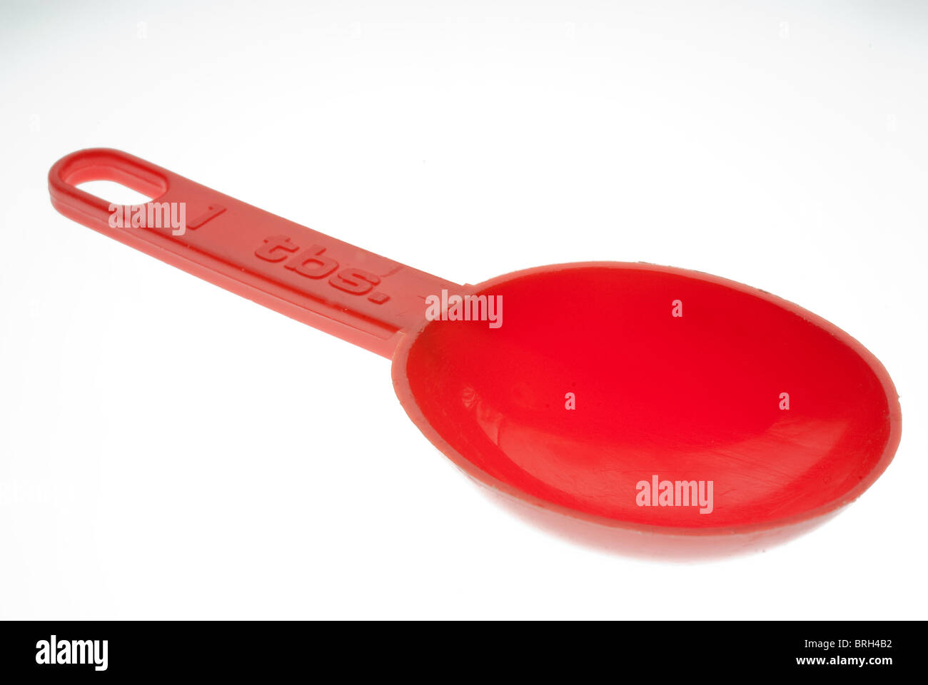 Red plastic tablespoon measure isolated on white Stock Photo - Alamy