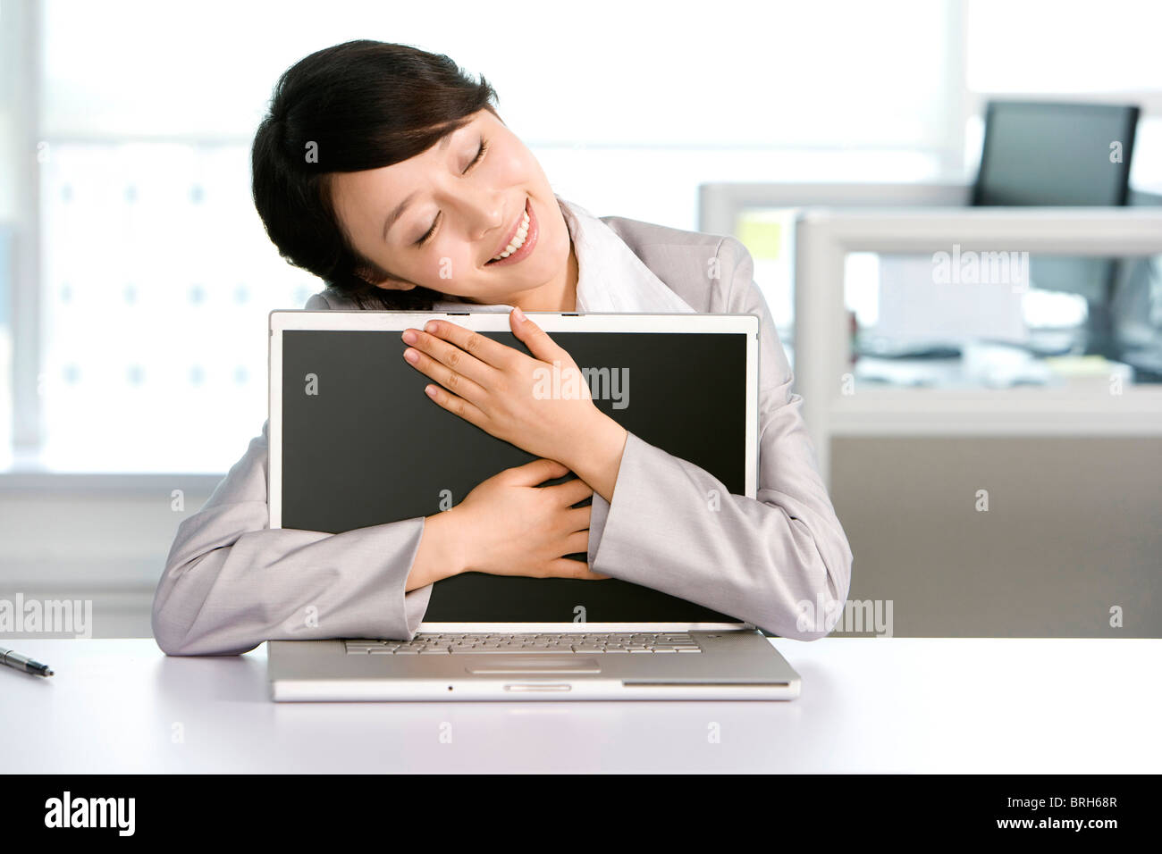 Office worker hugging her computer Stock Photo - Alamy