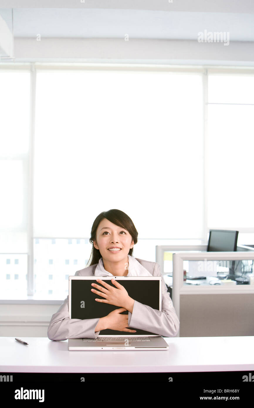 Office worker hugging her computer Stock Photo - Alamy