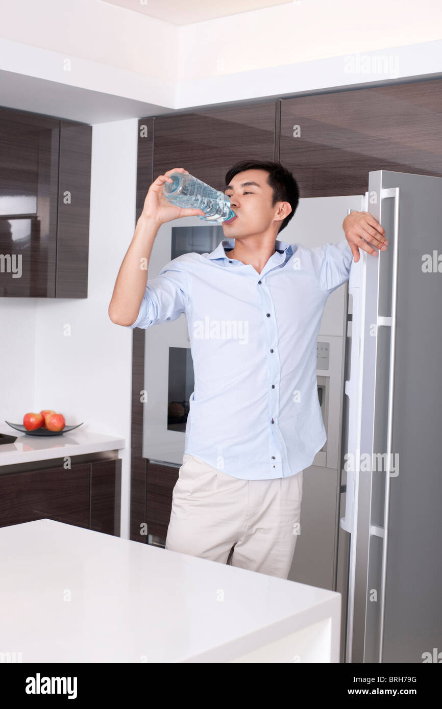 Man drinking a bottle of water in the kitchen Stock Photo - Alamy