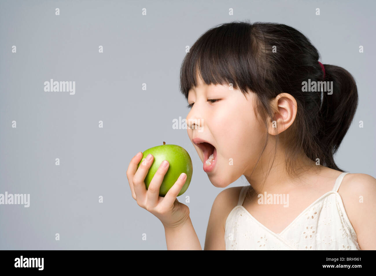 Girl about to bite into an apple Stock Photo - Alamy