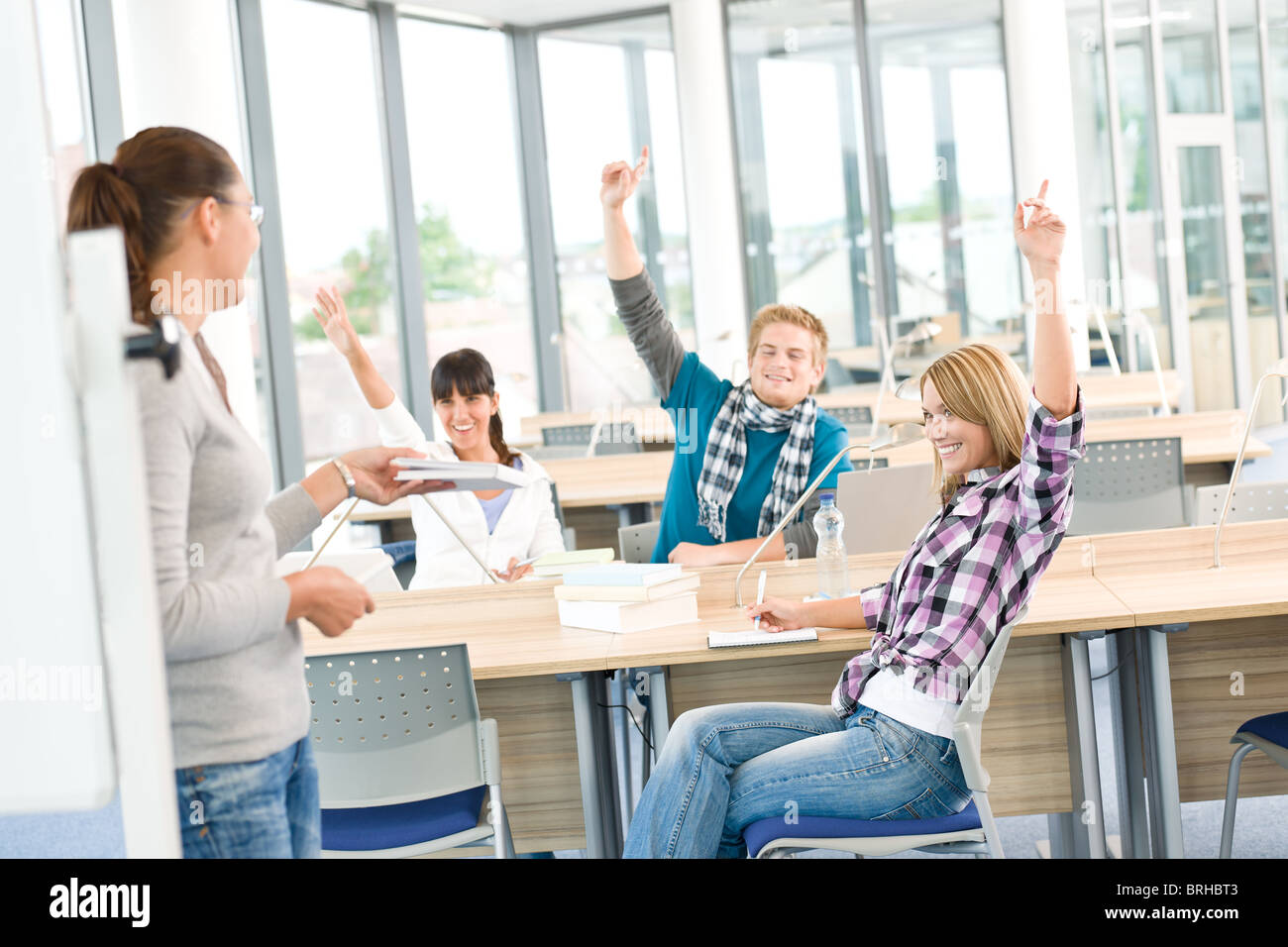 High school students raising hands, in classroom with professor Stock ...
