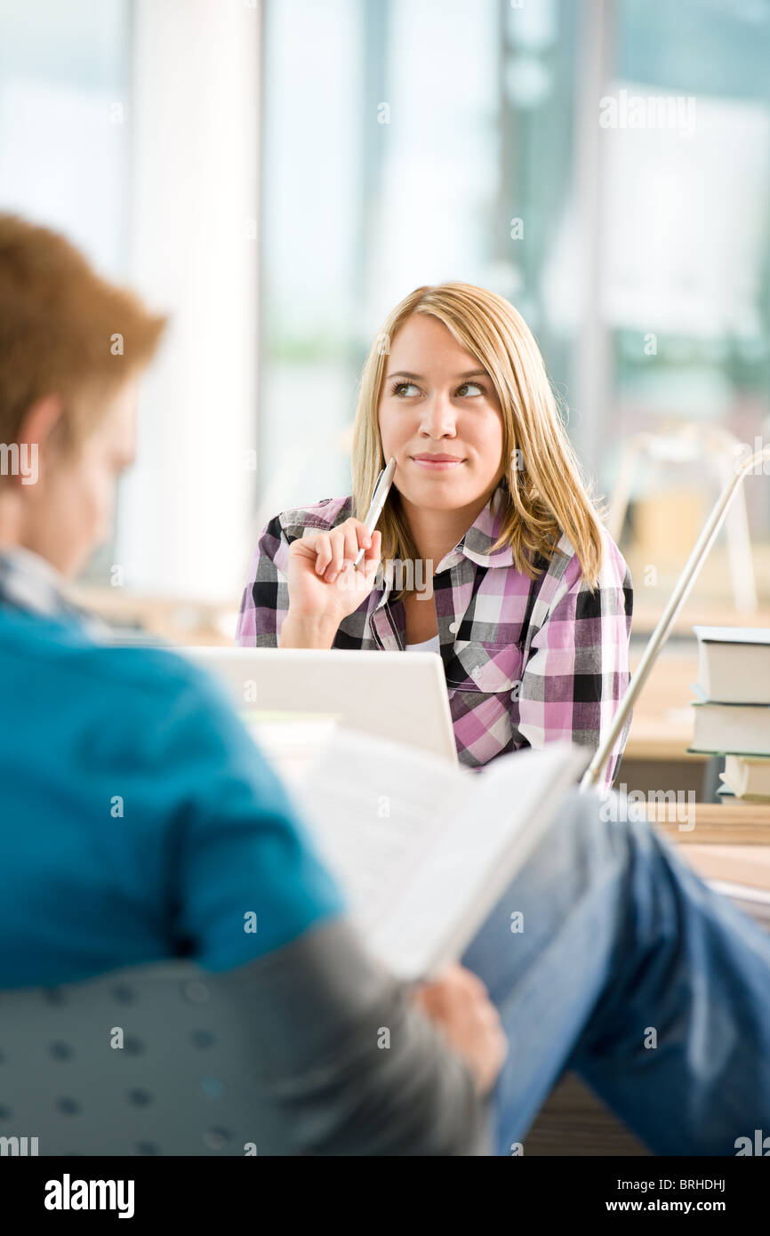 Two students with books and laptop in classroom studying Stock Photo ...
