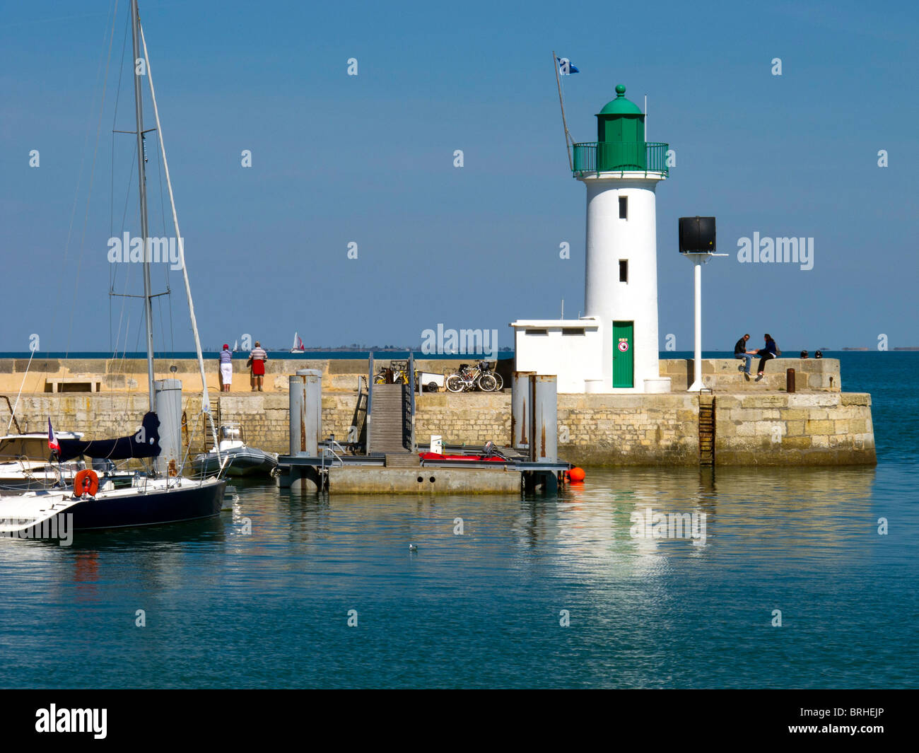 The white lighthouse with green top at the entrance to the harbour in ...