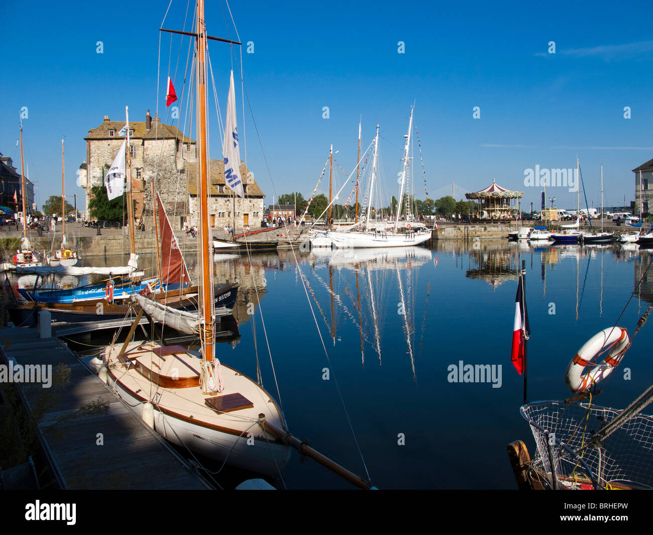 The old port in Honfleur, France showing moored yachts, a merry go ...