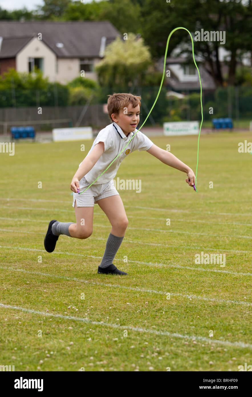 Boy in skipping race on grass field on school sports day Stock Photo ...