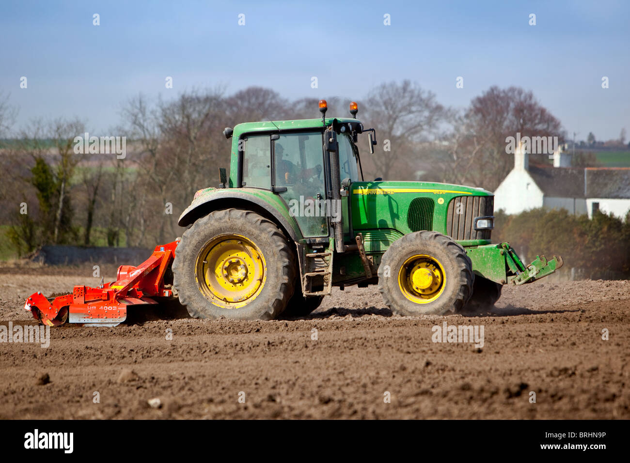 Tractor harrowing field after plowing in preparation for spring sowing ...