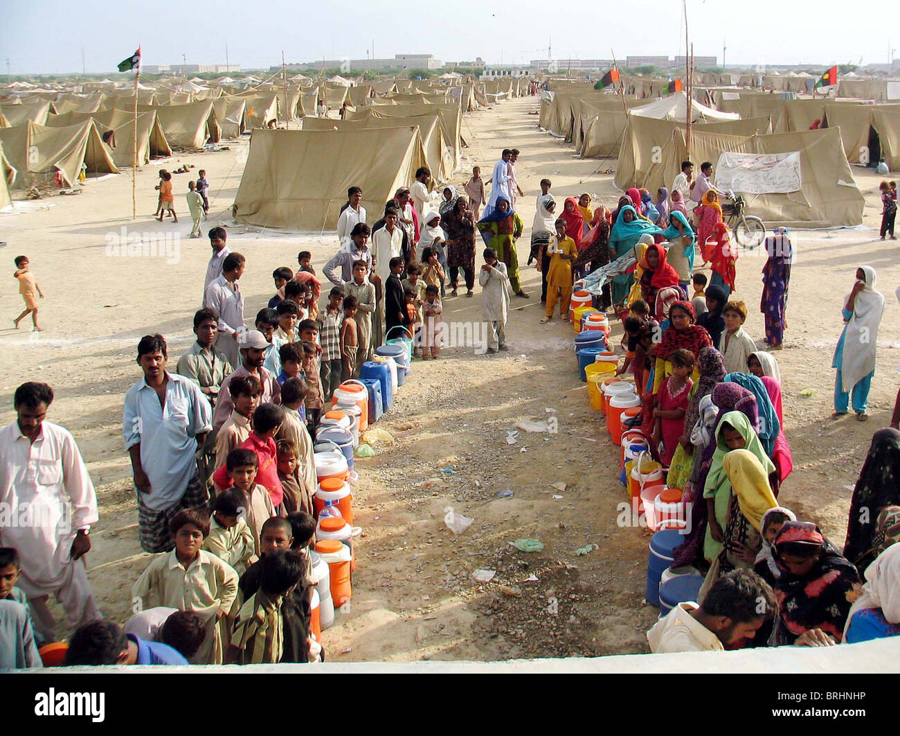 Flood affected people with their drinking water coolers stand in queues ...