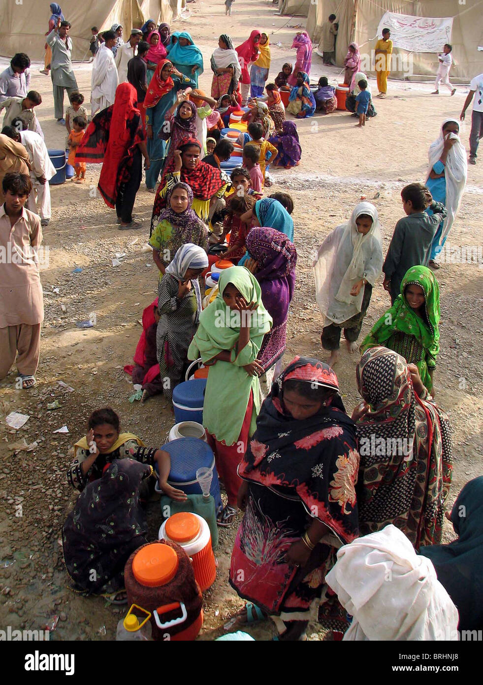 Flood affected people with their drinking water coolers stand in queues ...