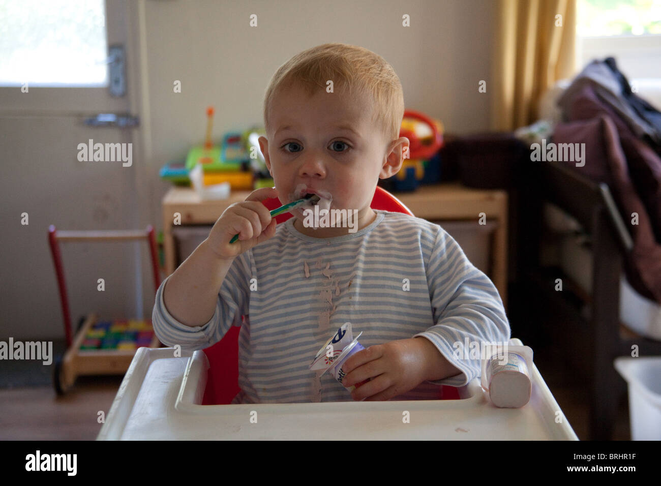 Young boy 16 months old eating a messily eating yogurt. Hampshire ...