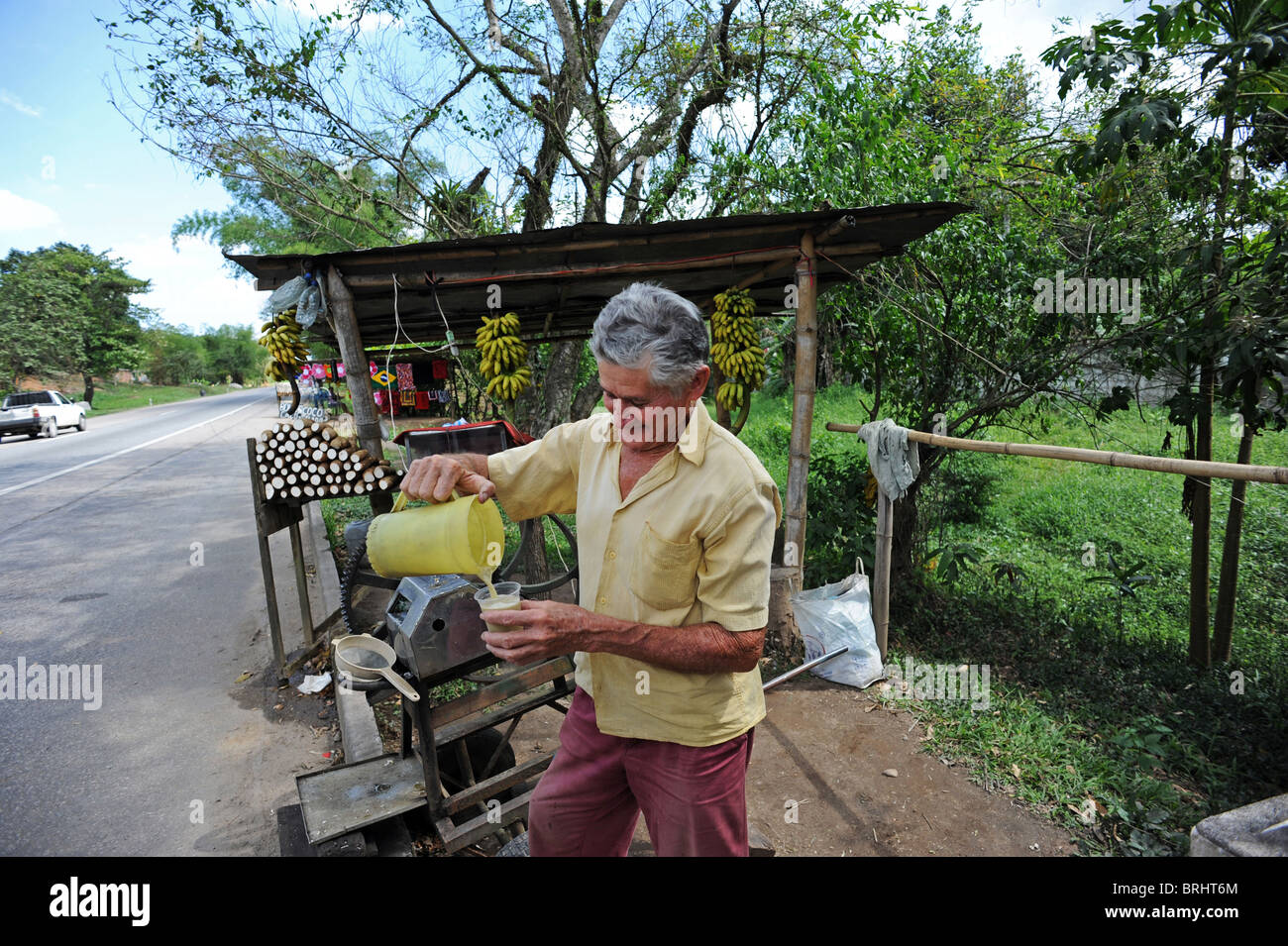 A man making juice from crushed sugar cane at the roadside on the ...