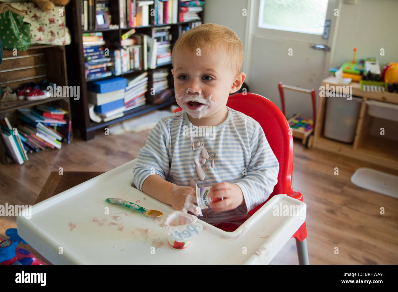 Young boy 16 months old eating a messily eating yogurt. Hampshire ...