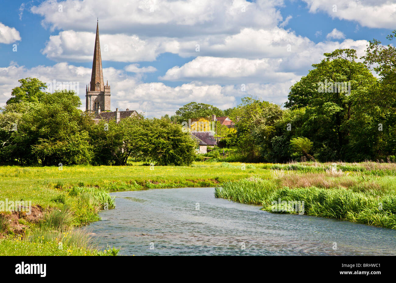 Summer view across meadow and River Windrush to St John the Baptist ...
