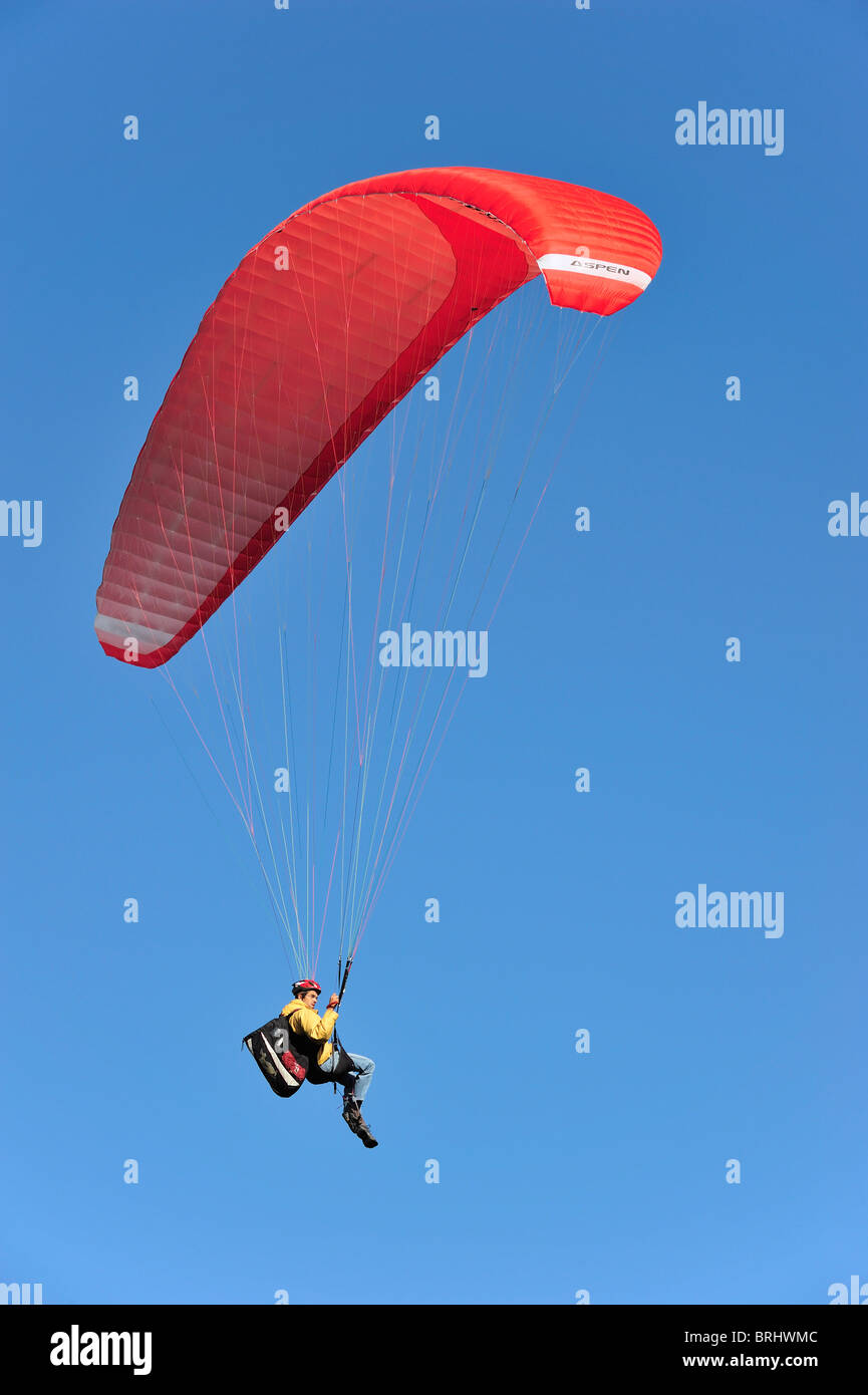 Paraglider in flight with red wing / canopy against blue sky Stock ...