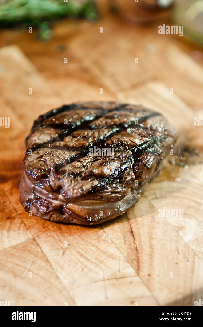 Beef steak griddled resting on chopping board Stock Photo - Alamy