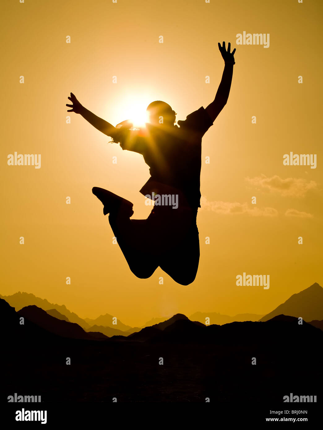 black silhouette of man in happy jump on orange sunset sky and desert ...