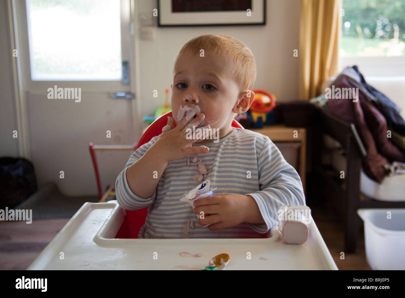 Young boy 16 months old eating a messily eating yogurt. Hampshire ...
