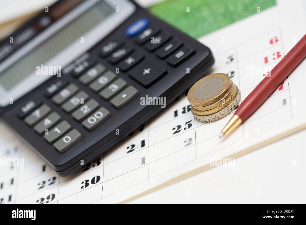 Calculator on the calendar page with coins and pen (credit; deposit ...