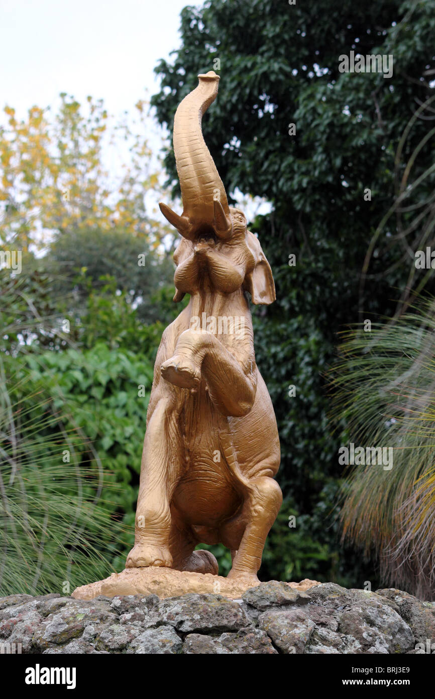 A GOLD COLOURED SCULPTURE OF A CROUCHED ELEPHANT TRUMPETTING IN A ...
