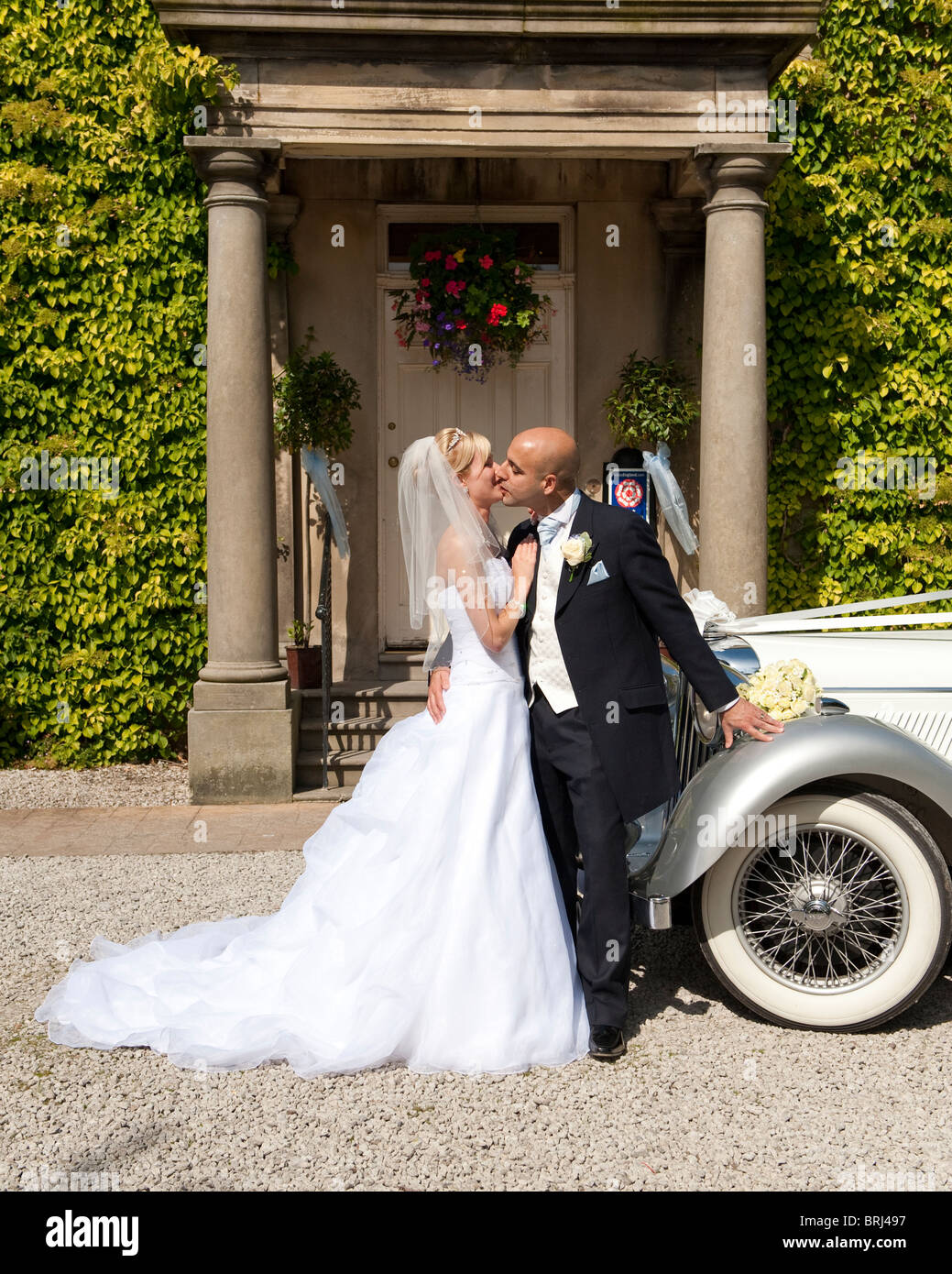 A stunning looking bride and groom next to a vintage wedding car Stock ...